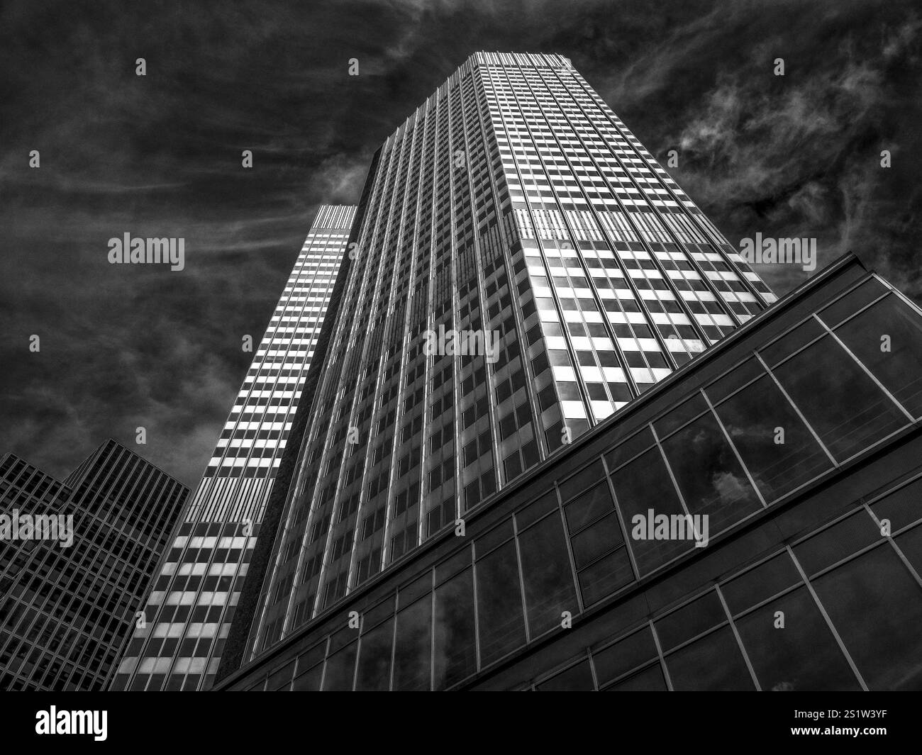 Dramatic black and white view of a modern tower block under a cloudy ...