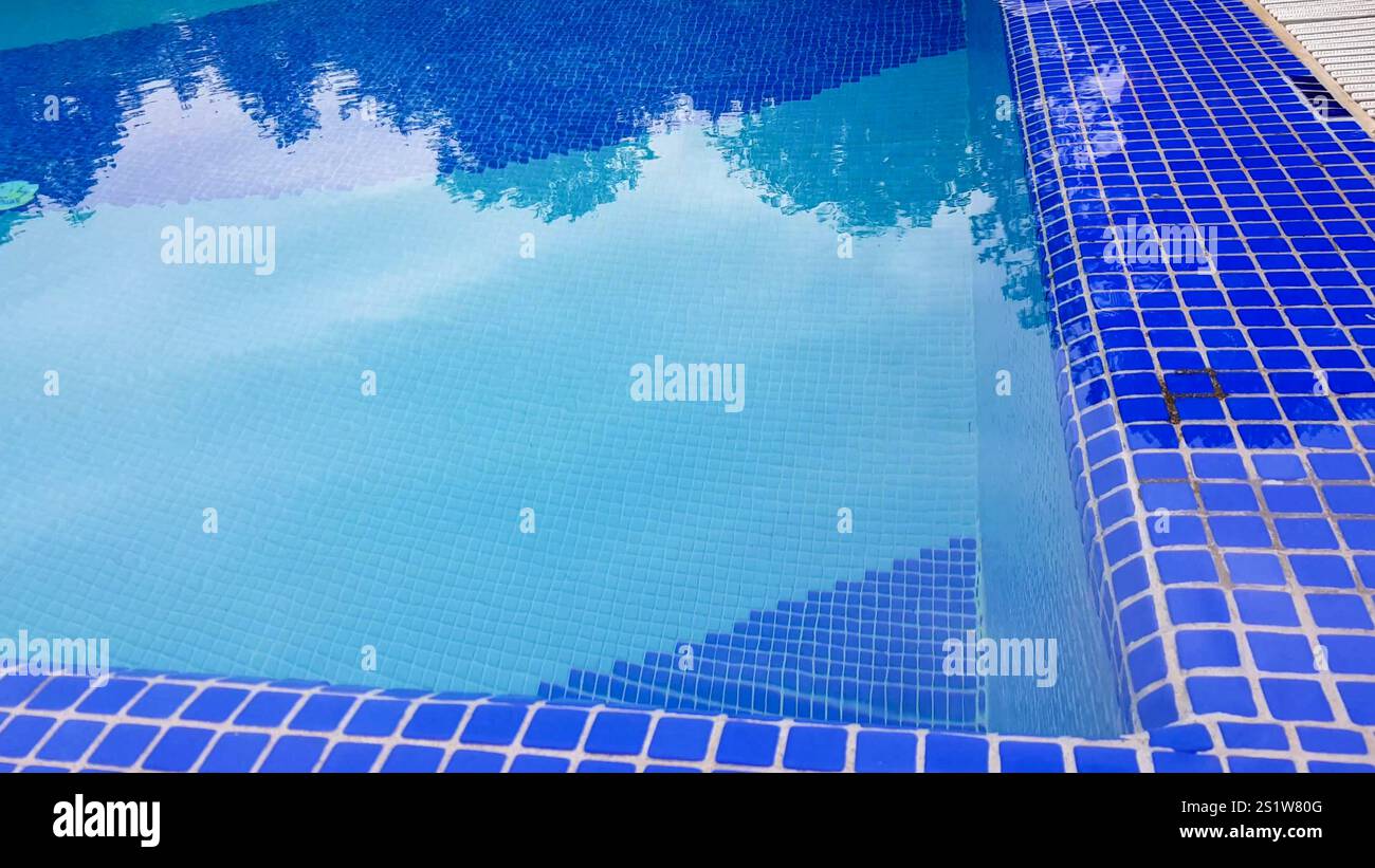 Blue water surface in an outdoor pool with blue mosaic tiles. The ...