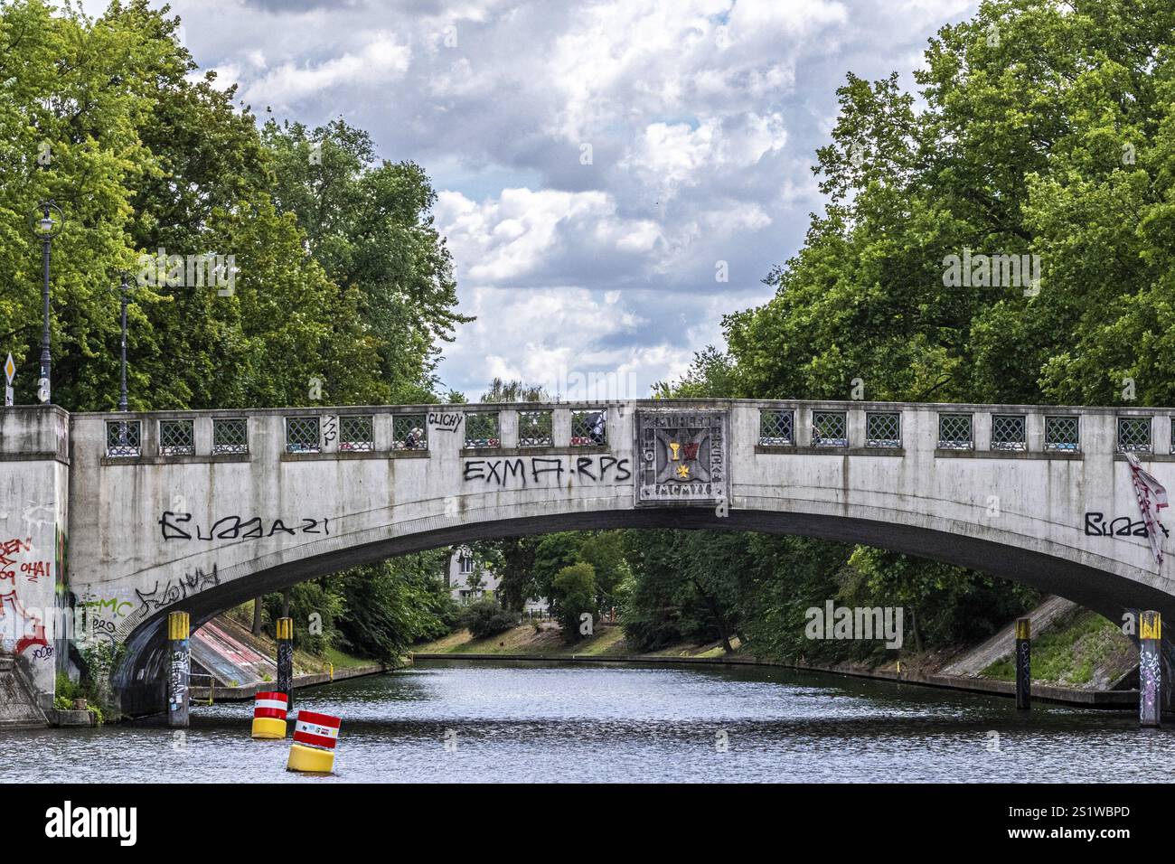 Stone bridge in Berlin in summertime with cloudy sky and trees in the ...