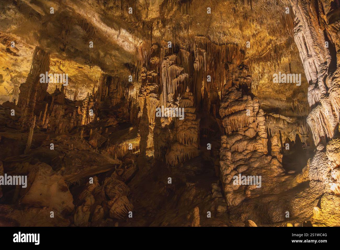 A cave with many stalactites and stalagmites. The cave is dark and the ...