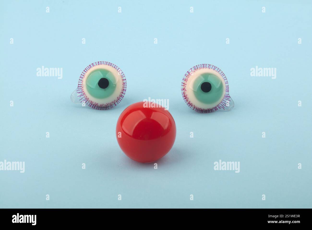Decorative fruit candy eyes with red nose over light blue background ...
