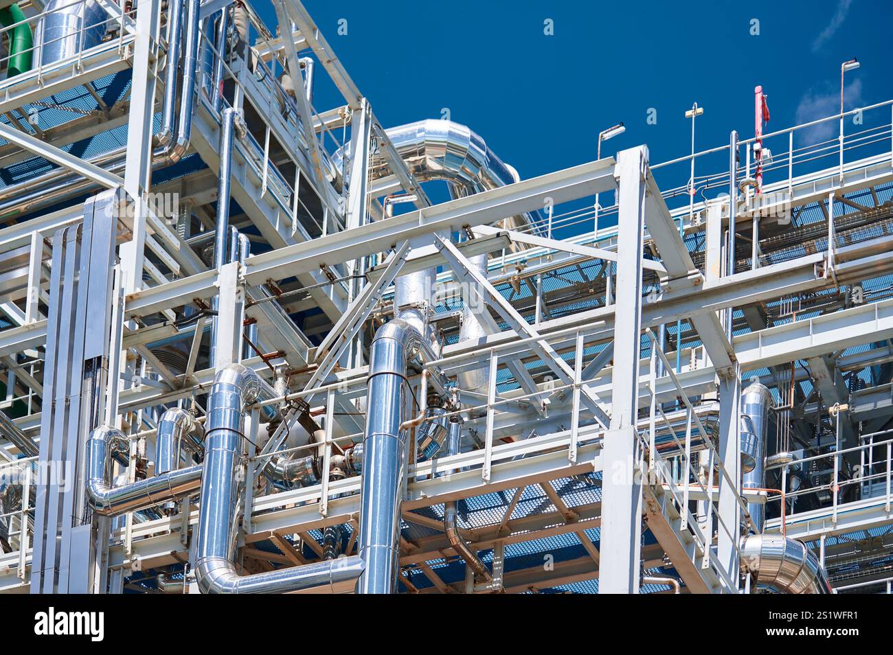Pipelines and structures of a chemical plant under a clear blue sky highlighting industrial ...