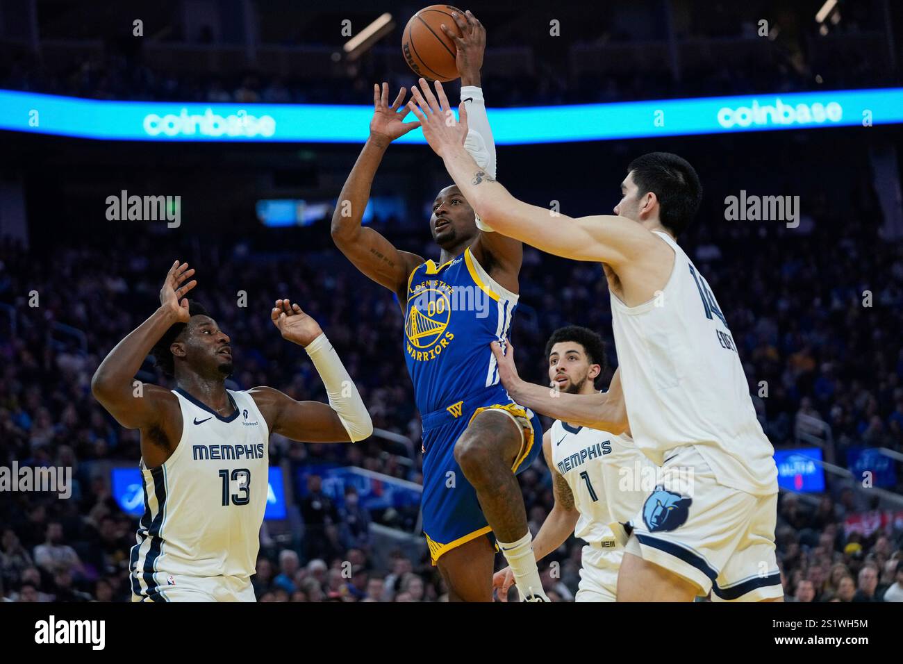 Golden State Warriors forward Jonathan Kuminga, center, looks to shoot between Memphis Grizzlies ...