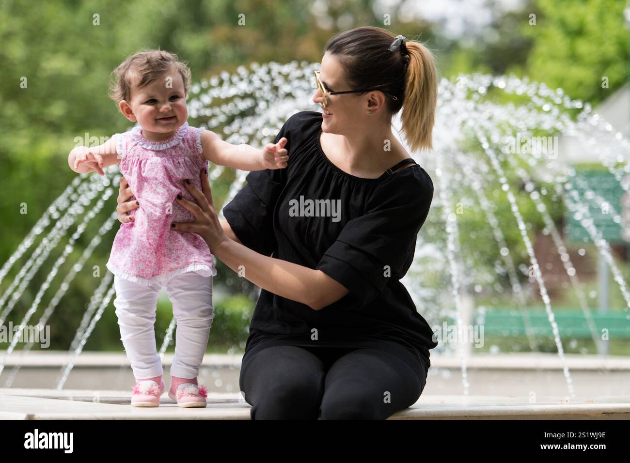 Loving Moment Of Mom And Baby With A Splashing Fountain Stock Photo - Alamy