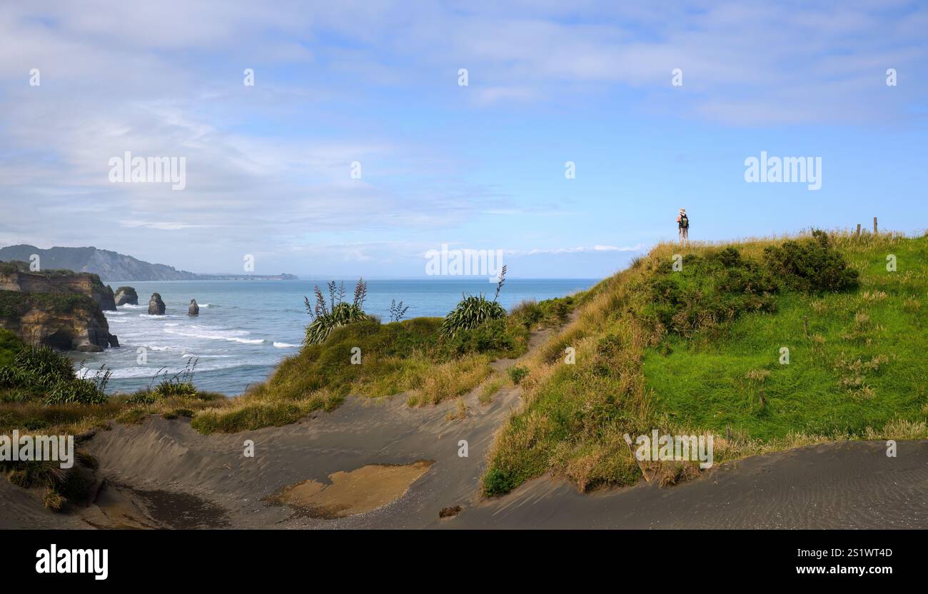 Three Sisters rock formation at Tongaporutu. Man standing on clifftop ...