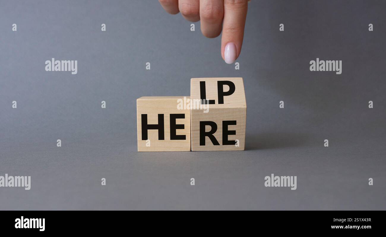 Help is here symbol. Businessman hand points at turned wooden cube with ...