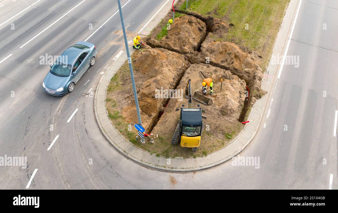 Aerial view of construction workers digging trenches on a roadside ...