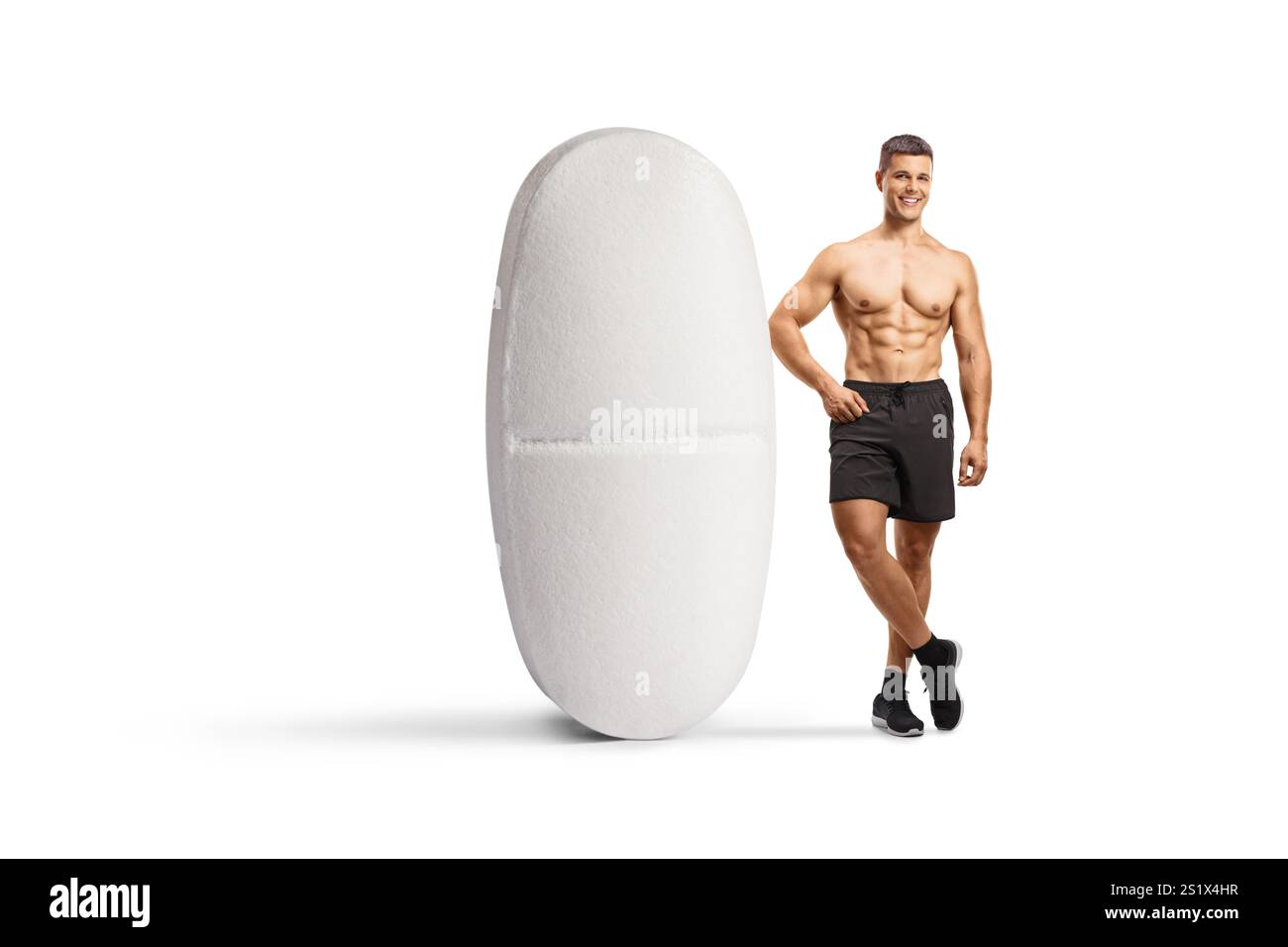 Full length portrait of a bodybuilder standing next to a big pill ...