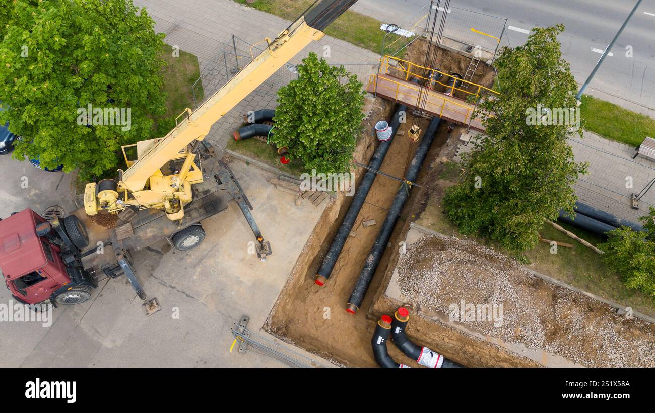 Aerial view of a construction site with a crane and large pipes being ...