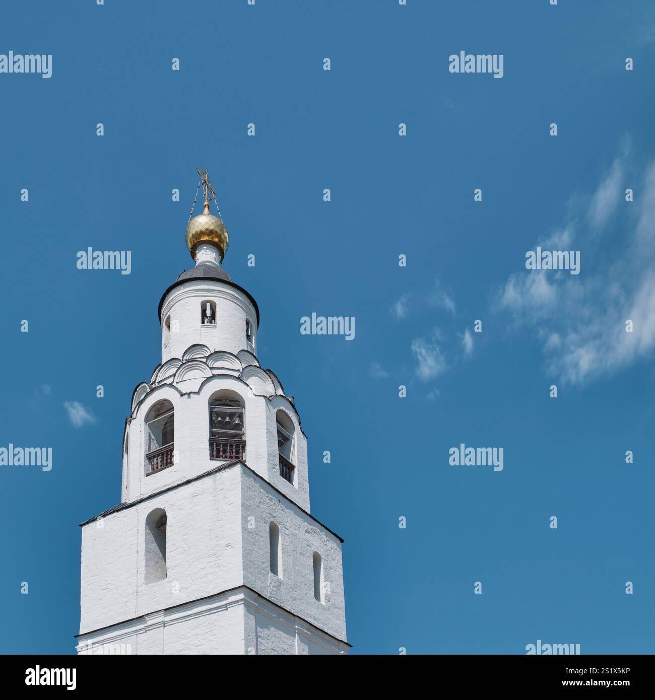 White Orthodox church bell tower with golden dome and cross ...