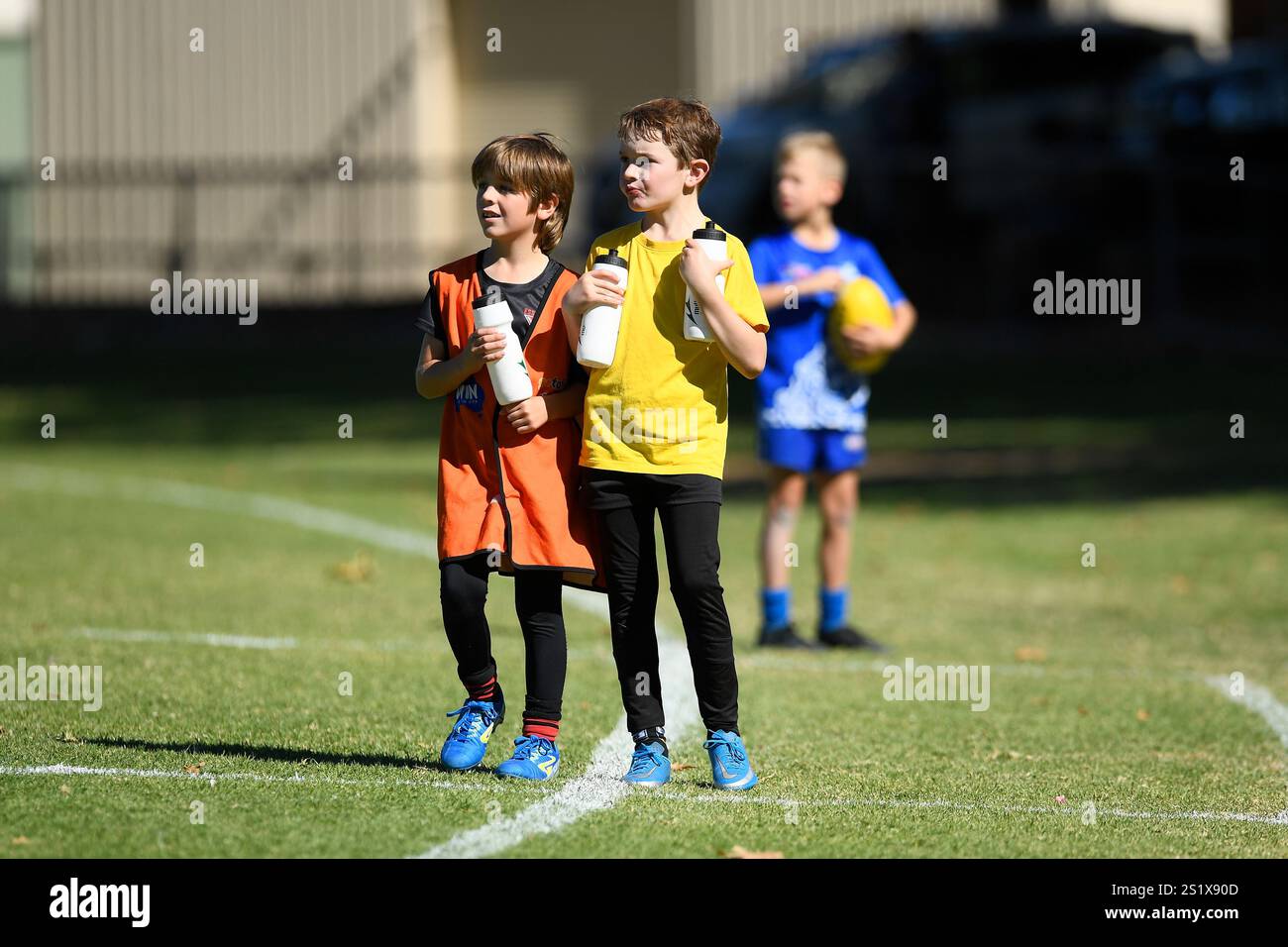 Three young football water boys hold their water bottles whilst ...