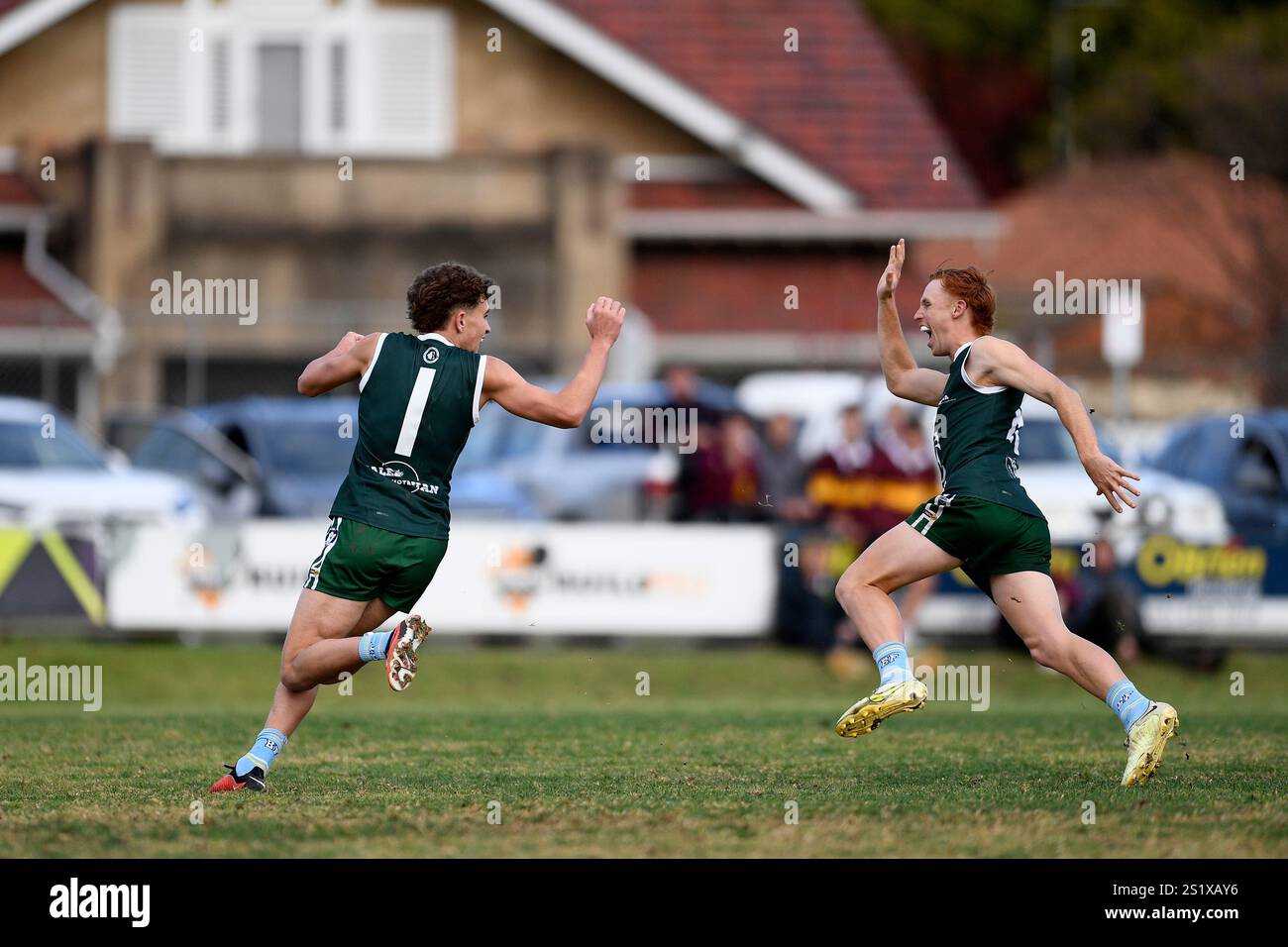 Two Australian rules football players run towards each other to ...