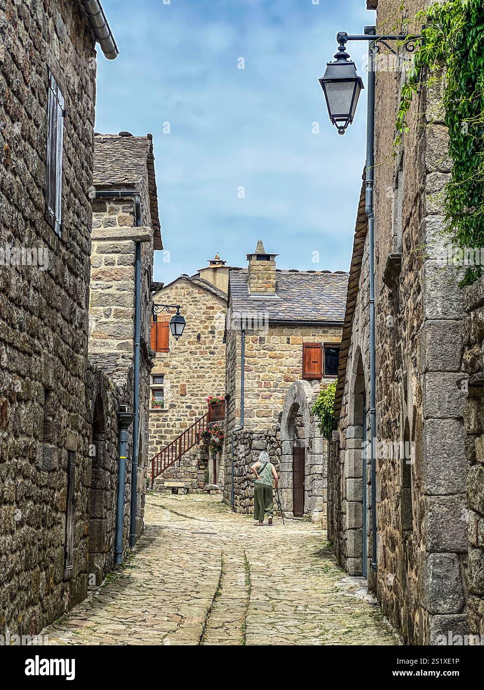 Woman is walking down a narrow cobblestone street in a historic french ...