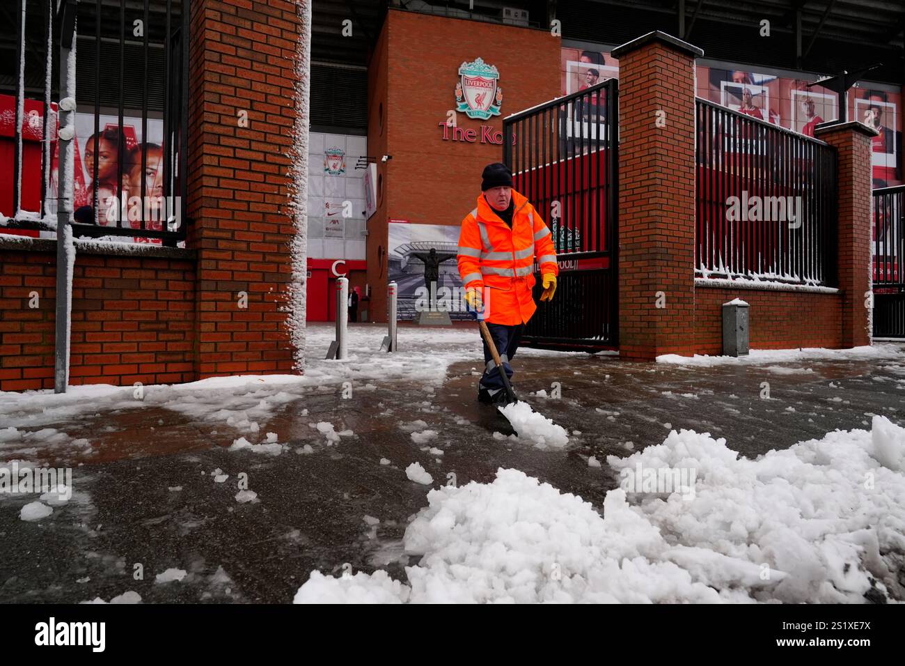 A worker clears snow from pathway at Anfield in Liverpool. Heavy ...