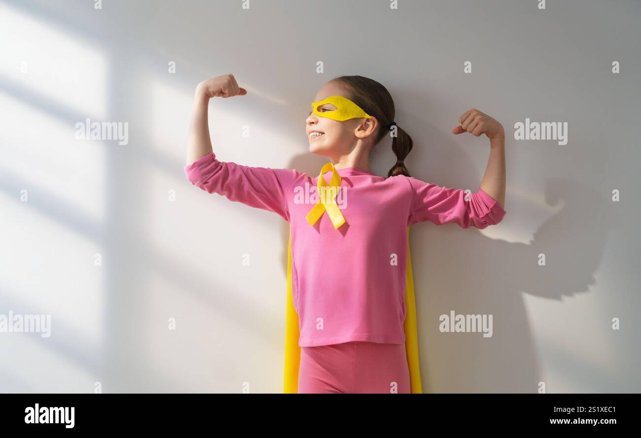 World Childhood cancer Day. Girl in superhero costume with golden ...