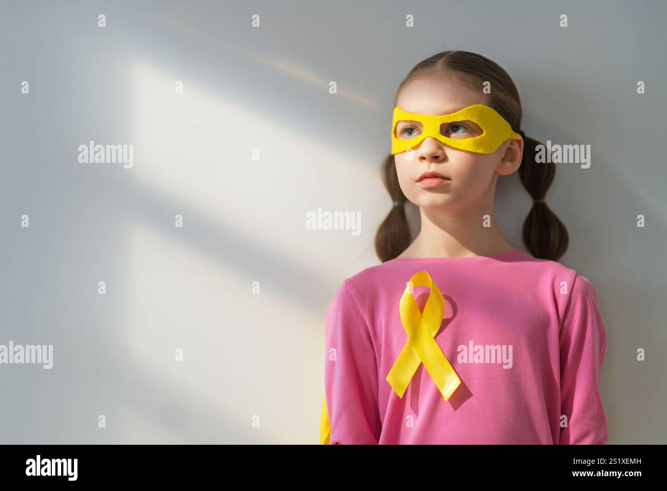 World Childhood cancer Day. Girl in superhero costume with golden ...