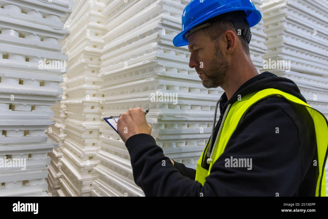 A worker wearing a helmet and safety vest checking the quality of ...