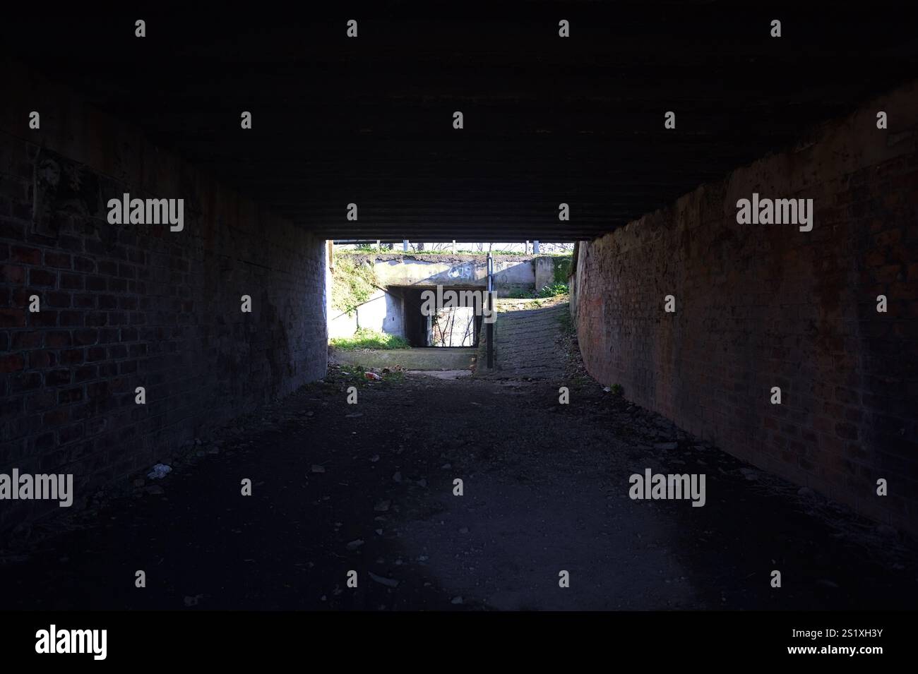 Dirt low passage in the shade under a concrete bridge with a lake at ...