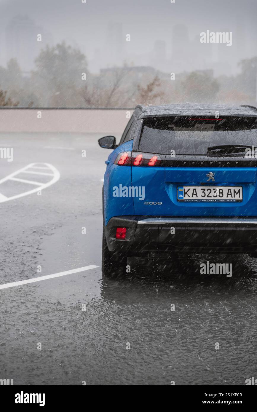 Blue Peugeot 2008 in the rain. Rear view of compact french crossover in ...