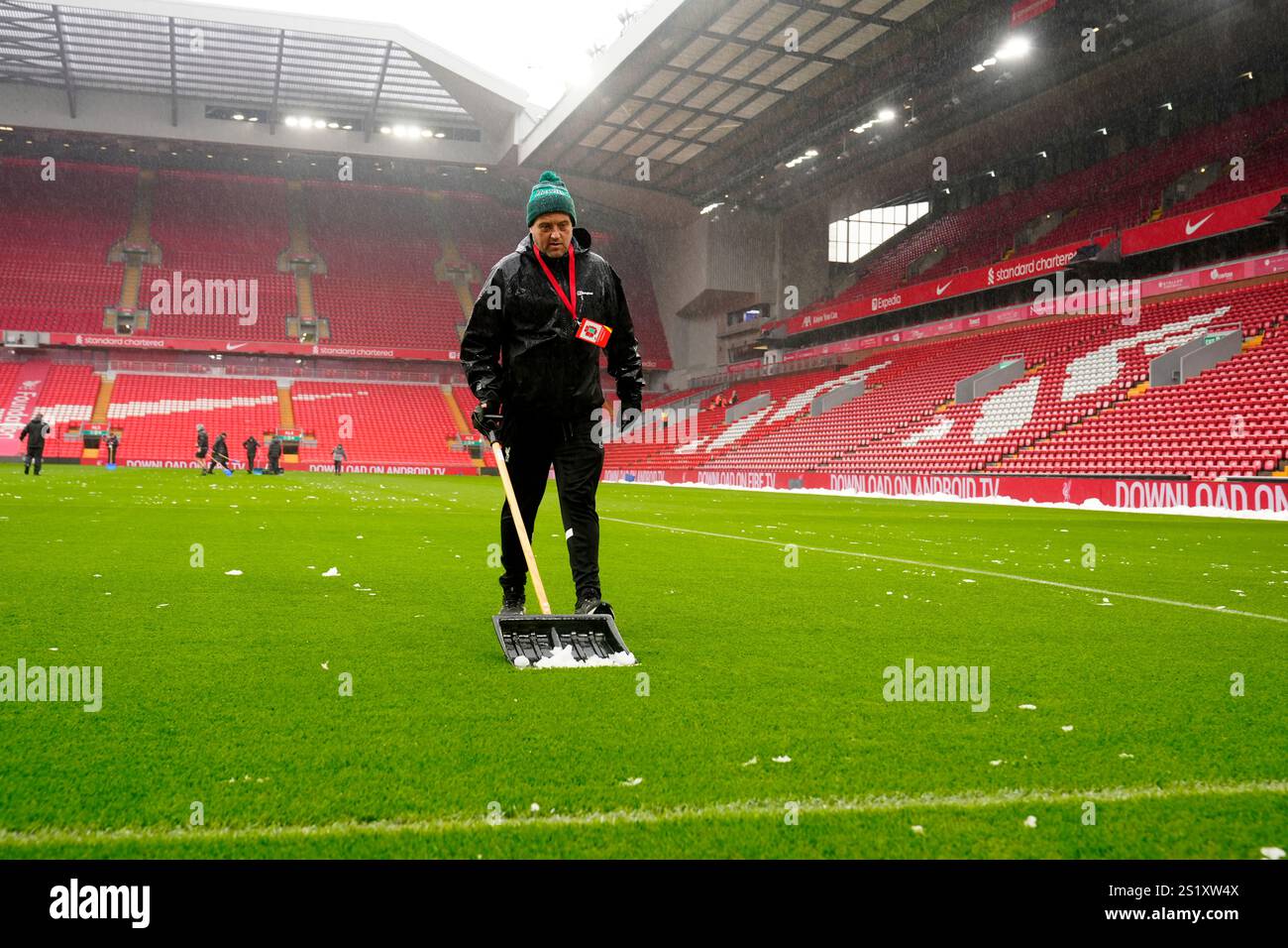 A member of the grounds crew uses a shovel to clear snow from the pitch ...