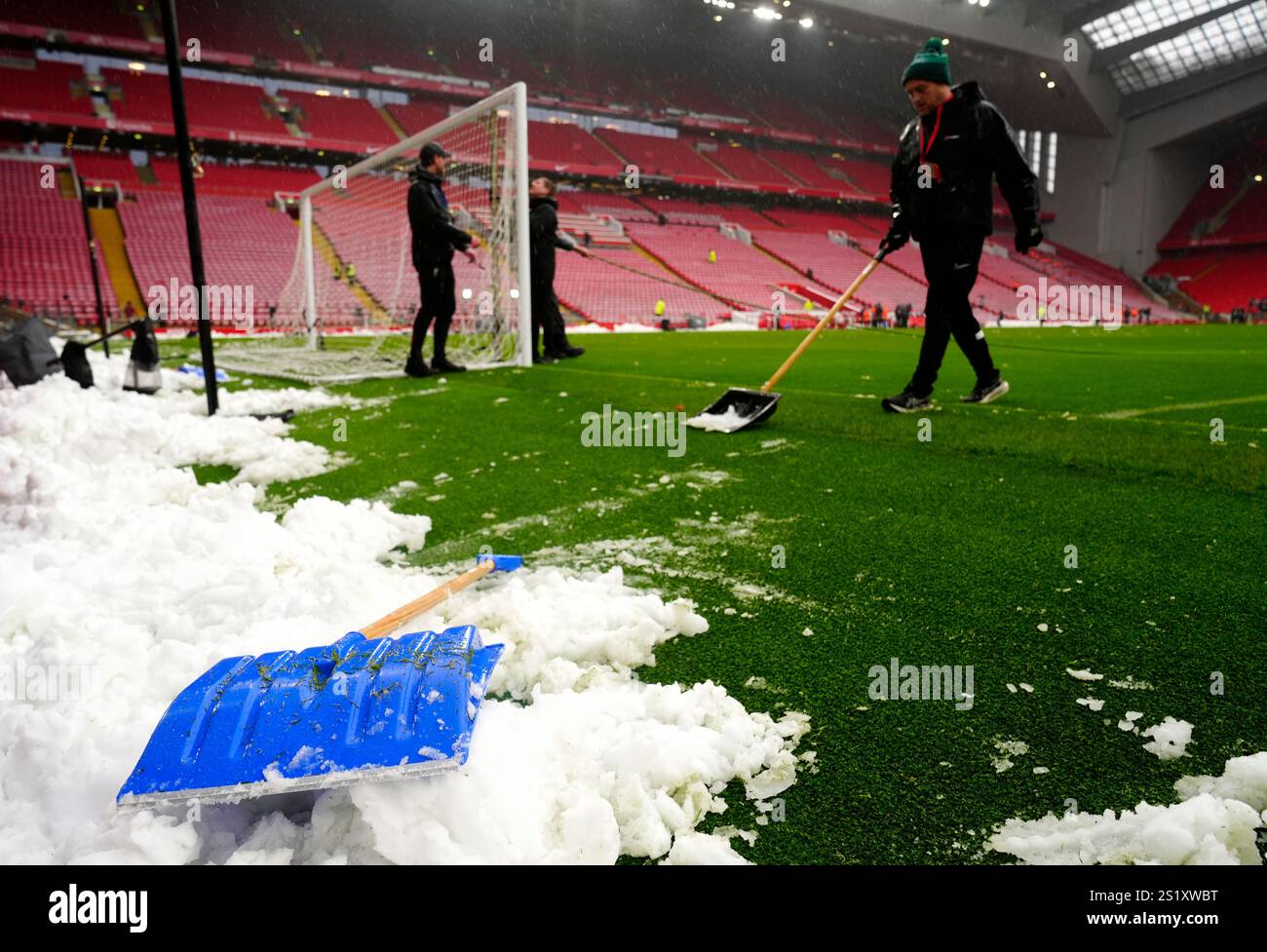Stewards shovel snow to the side of the pitch ahead of the Premier ...