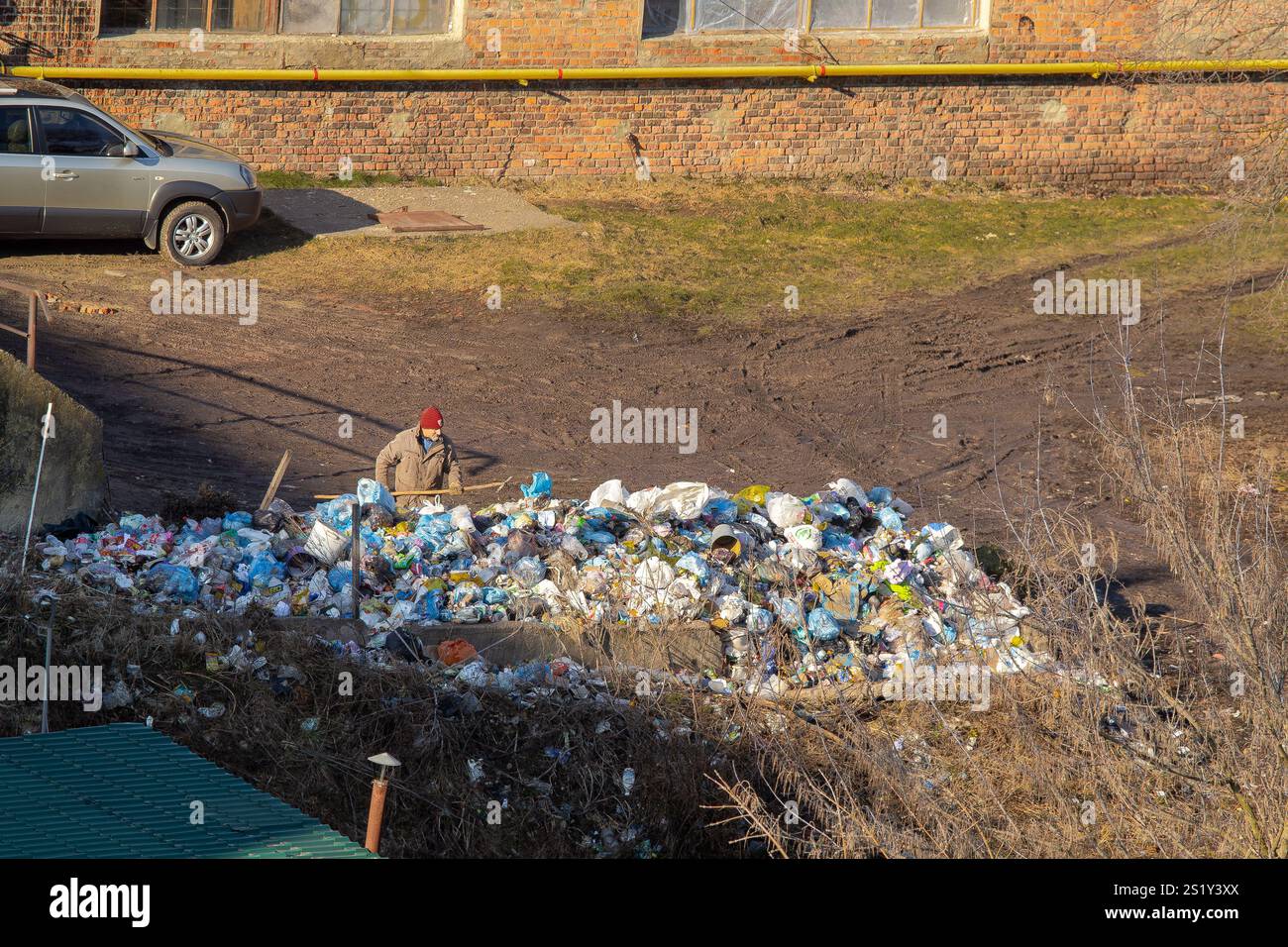 A man sorts through garbage at an informal dump in an urban landscape ...
