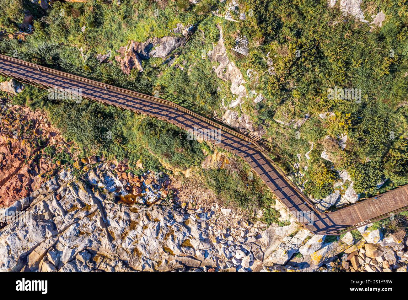 wooden pedestrian footbridge over a coastal rocky soil, aerial top view ...