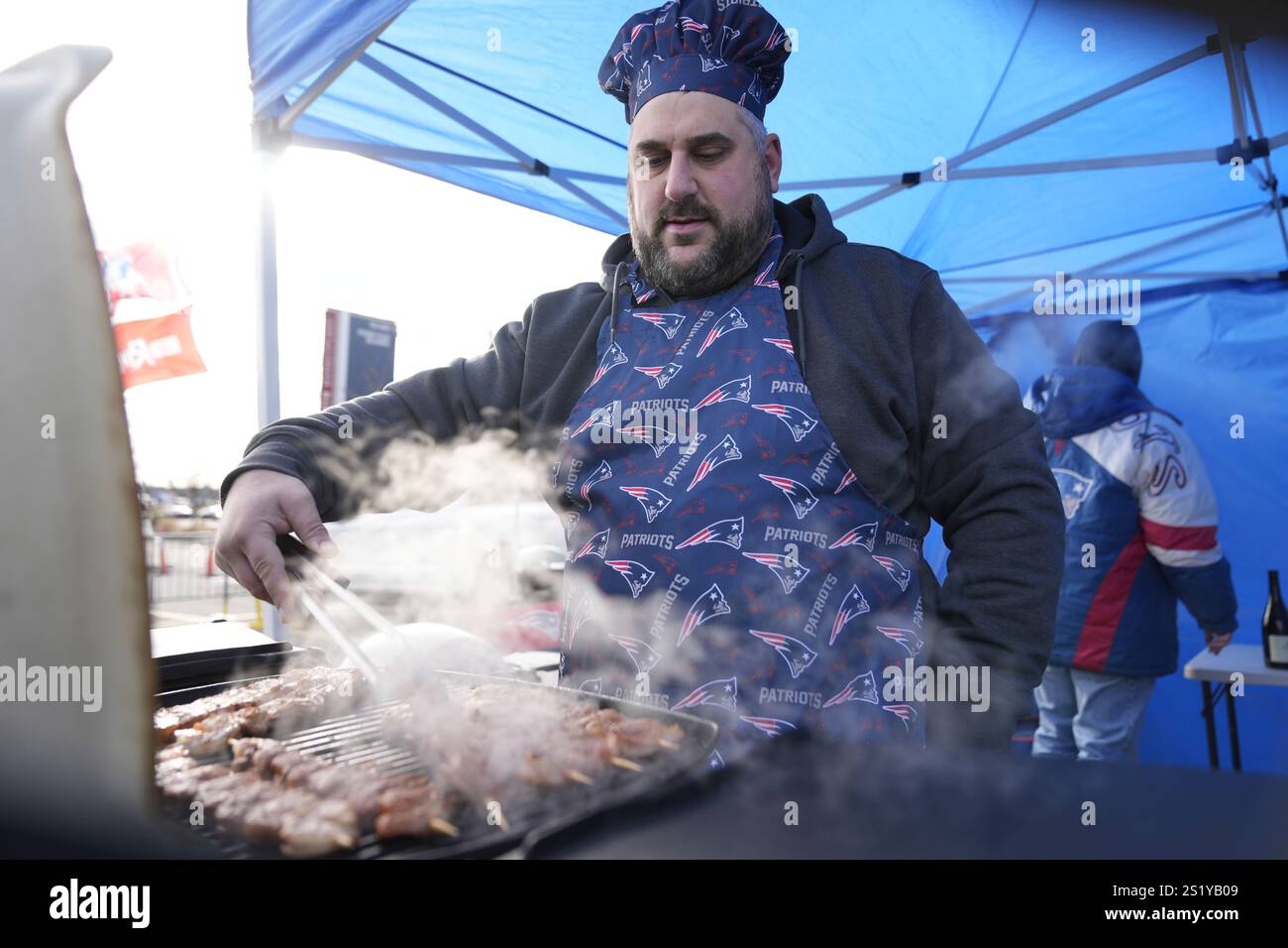 Adam Hirsch, of Wayland, Mass., tends the grill while tailgating prior ...