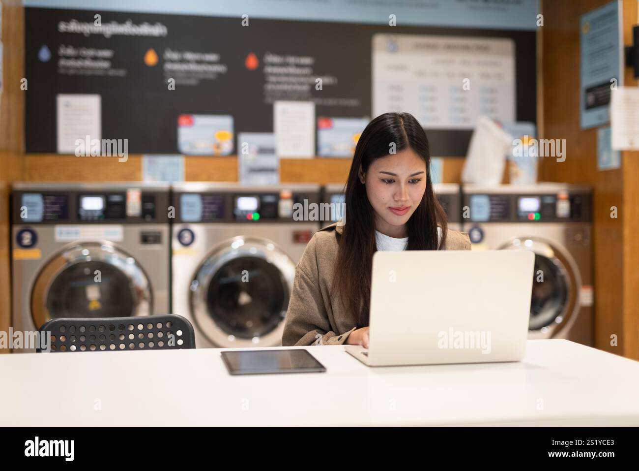 Woman working on laptop in laundry shop concept Stock Photo - Alamy