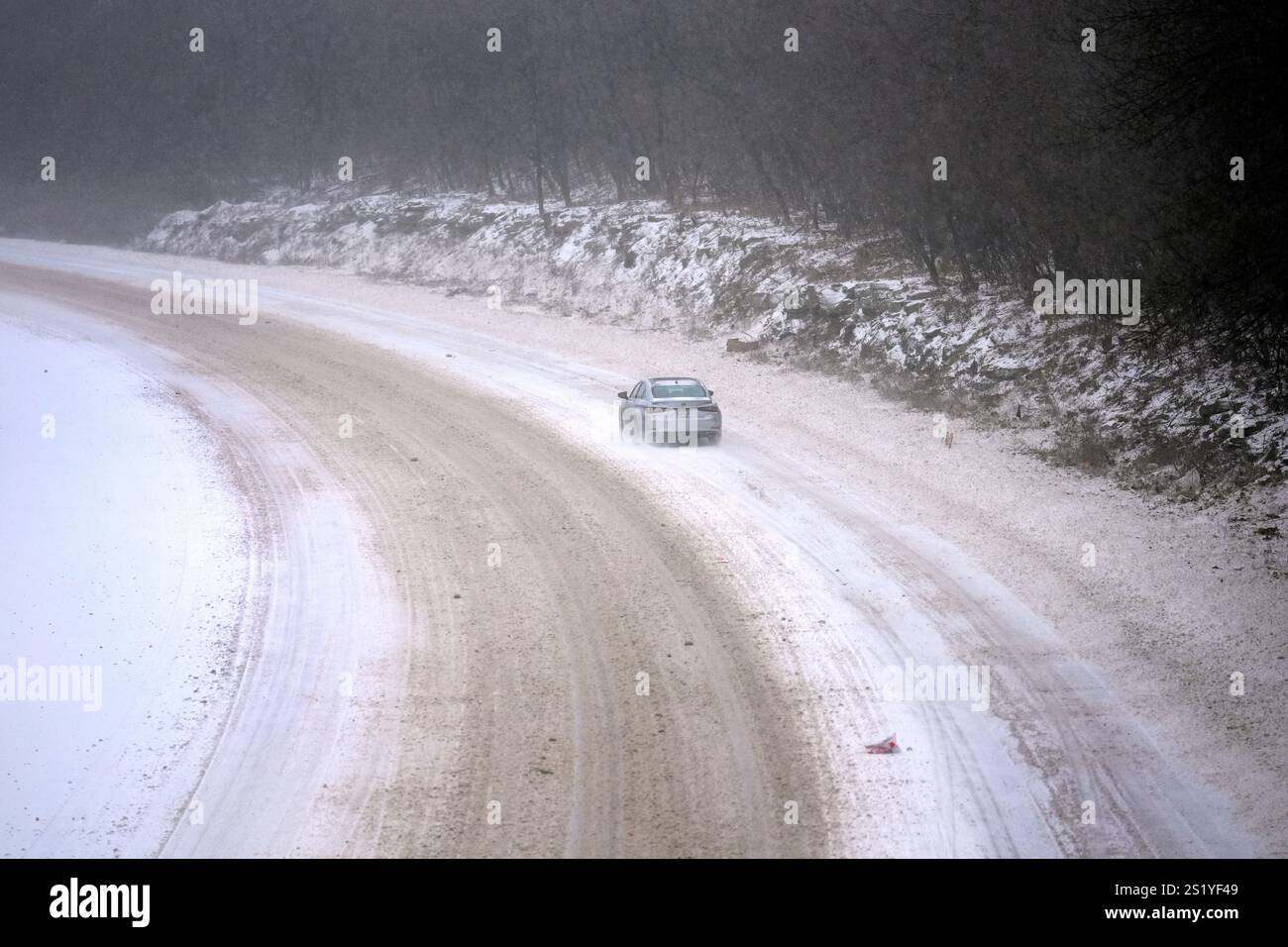 A car slowly navigates a snow-covered interstate Sunday, Jan. 5, 2025 ...