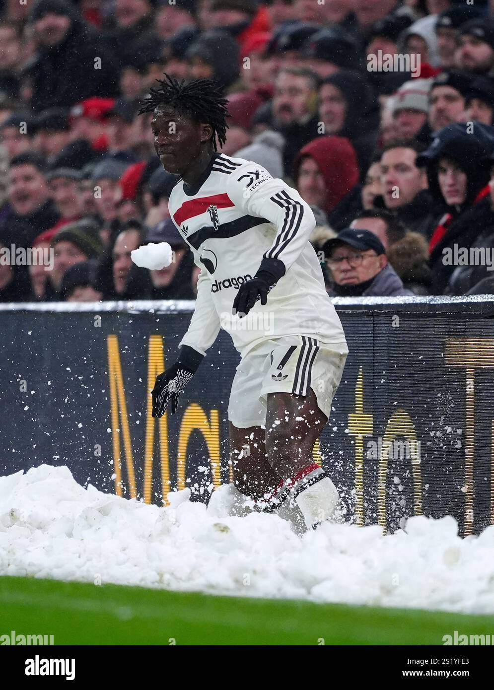 Manchester United's Kobbie Mainoo slides into a bank of snow on the ...
