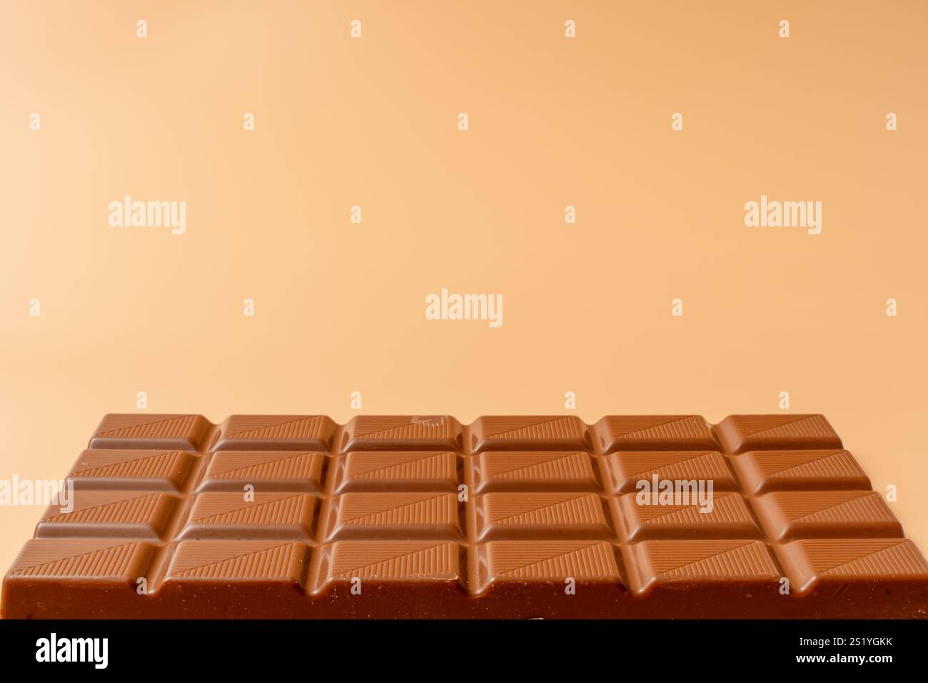 A chocolate bar with a white background. The chocolate bar is cut into ...