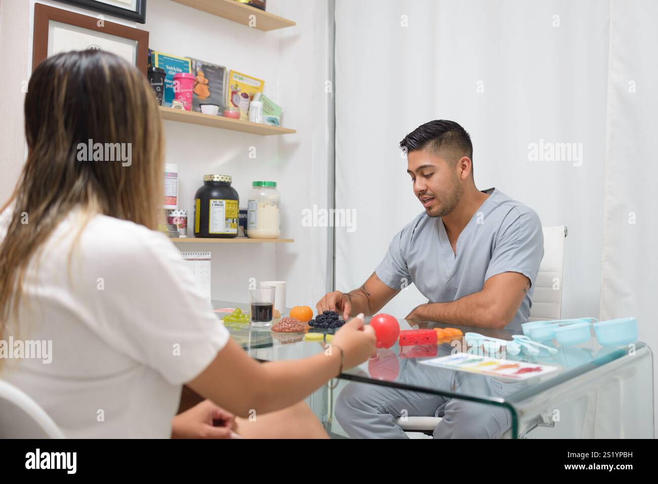 A nutritionist explains portion control to a patient using cup ...