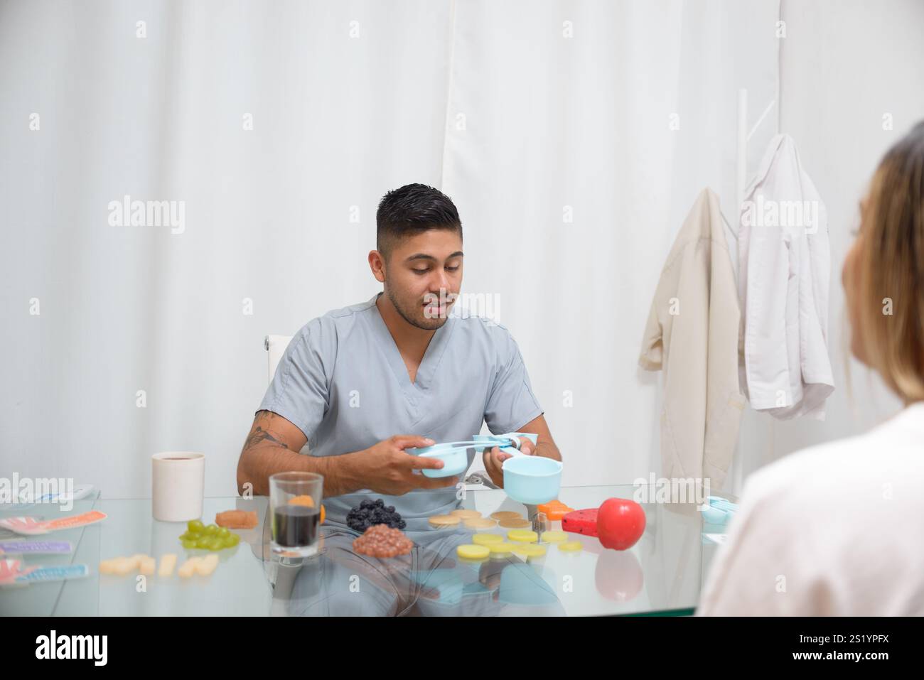 A nutritionist explains portion control to a patient using cup ...
