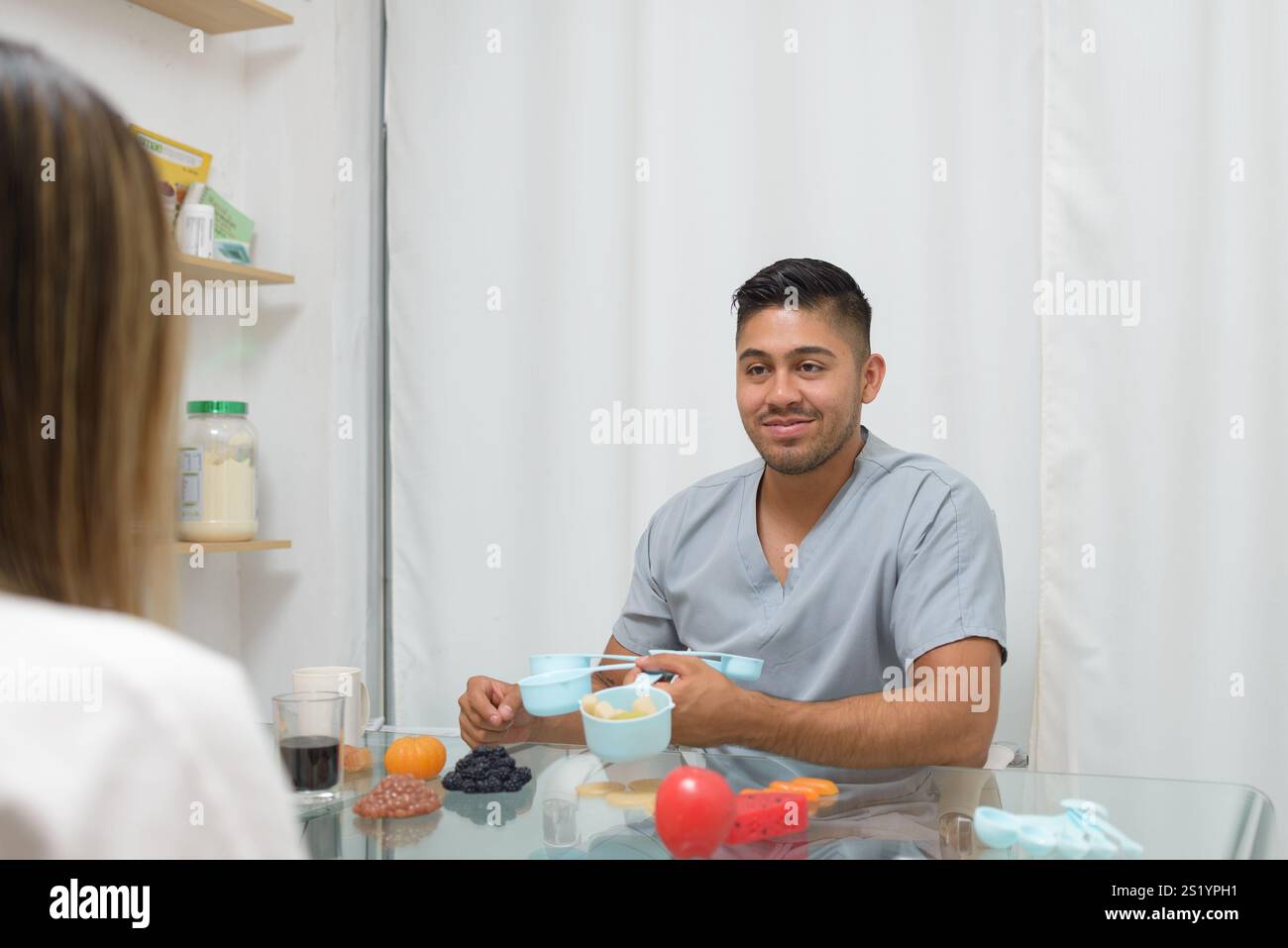 A nutritionist explains portion control to a patient using cup ...