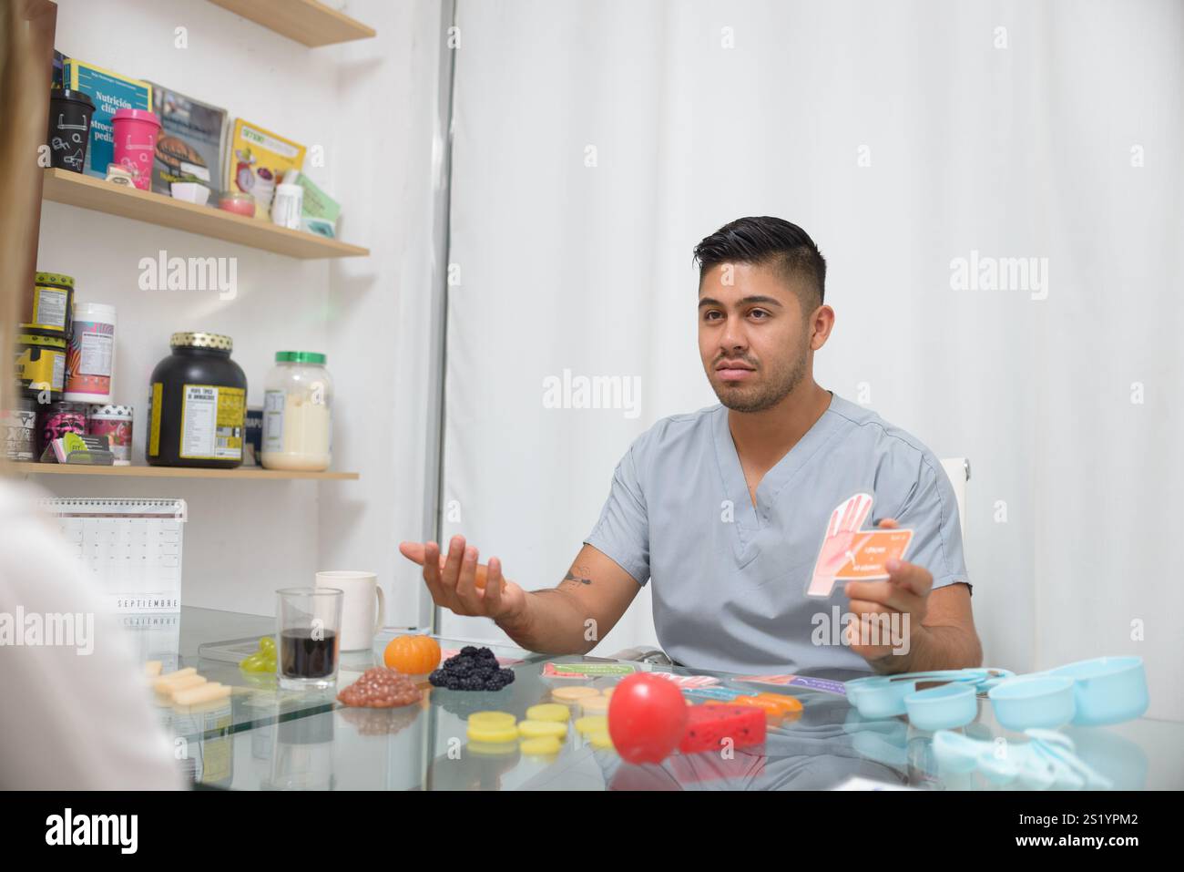 A nutritionist explains portion control to a patient using cup ...