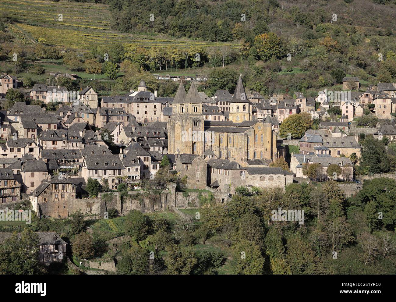 In Conques, France, medieval buildings stand tall among lush greenery ...