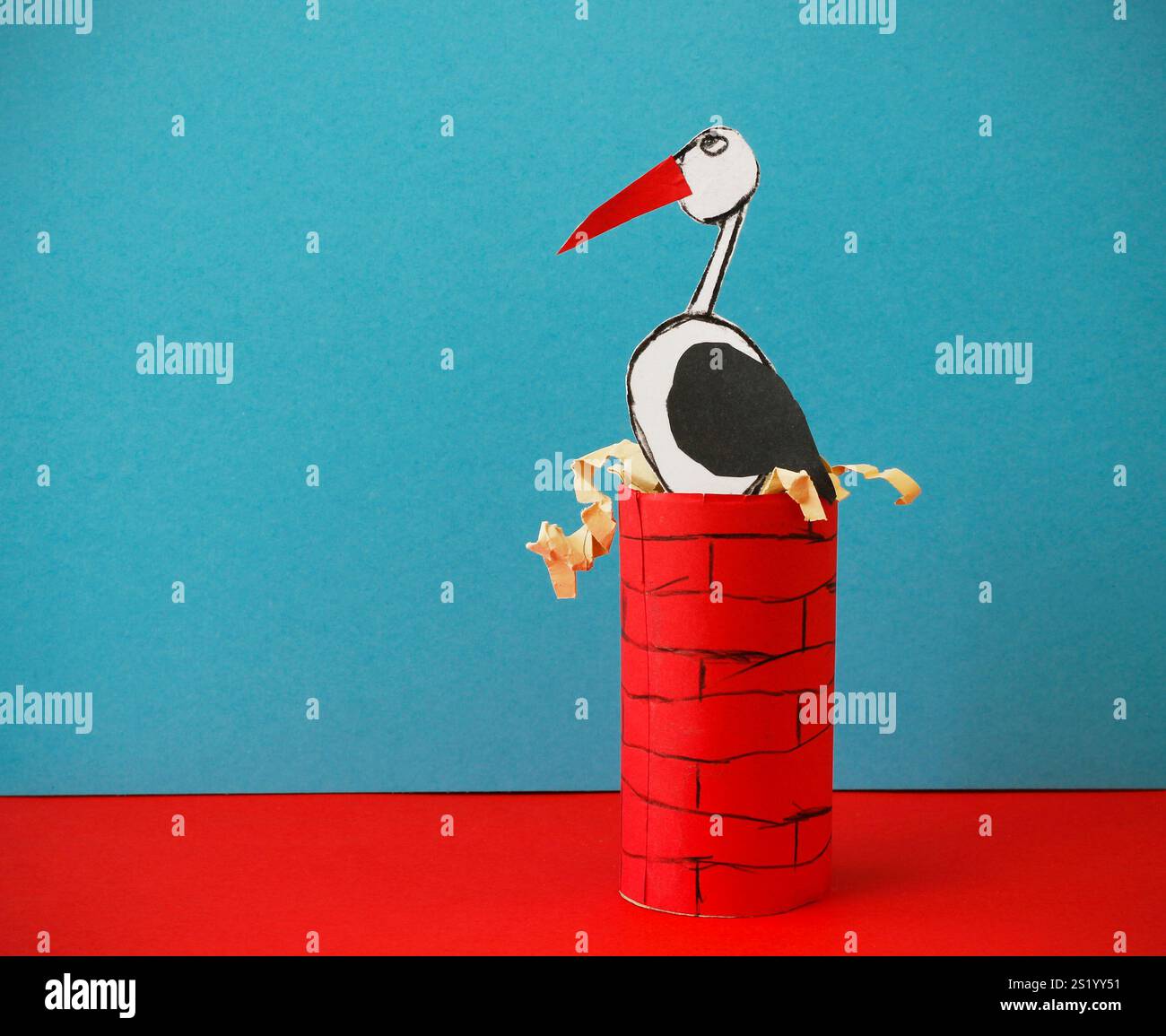 A stork sitting in a nest on a chimney made by a child from a roll of ...