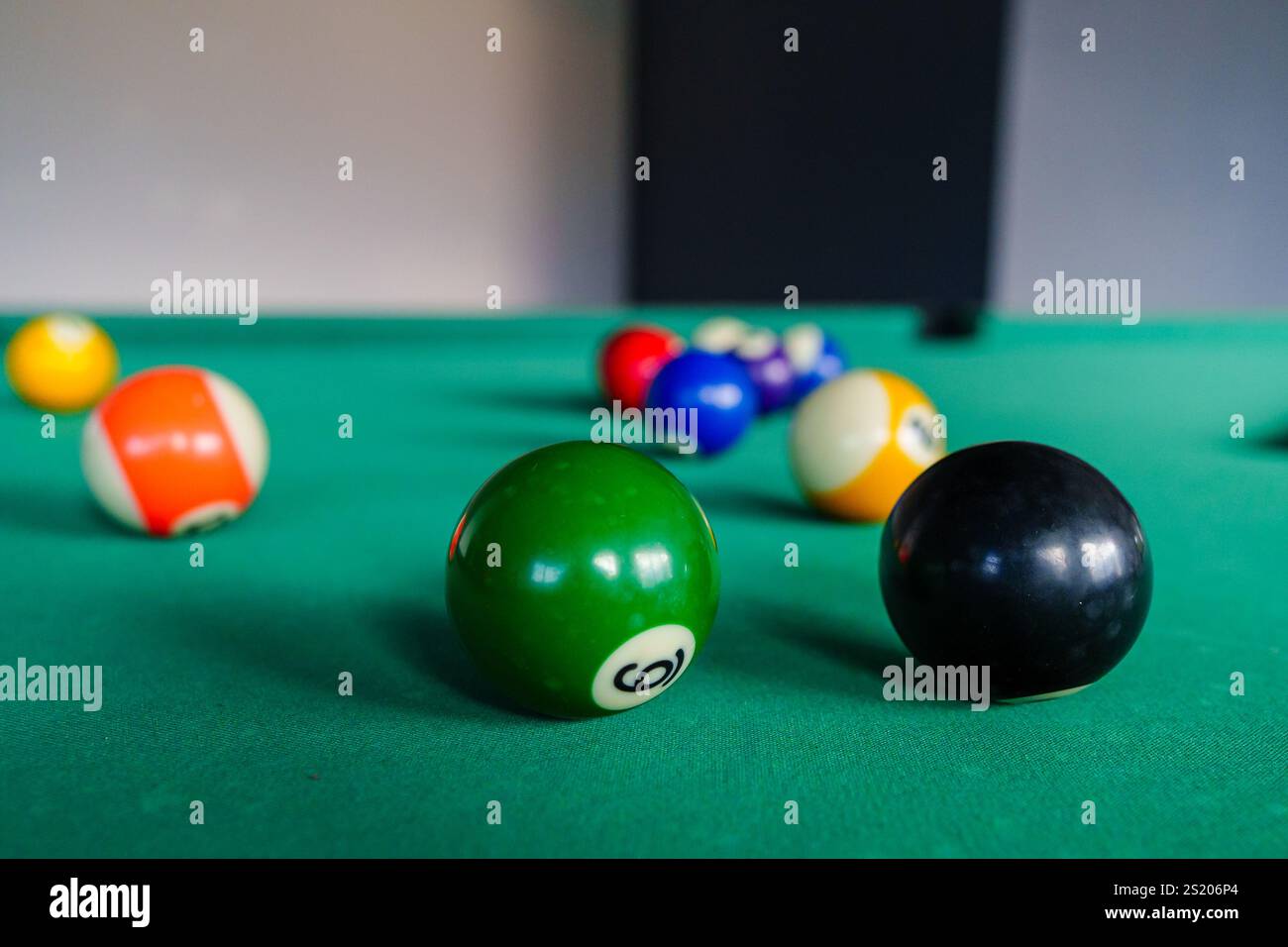 A close-up shot of a pool table highlighting an eight ball in focus ...