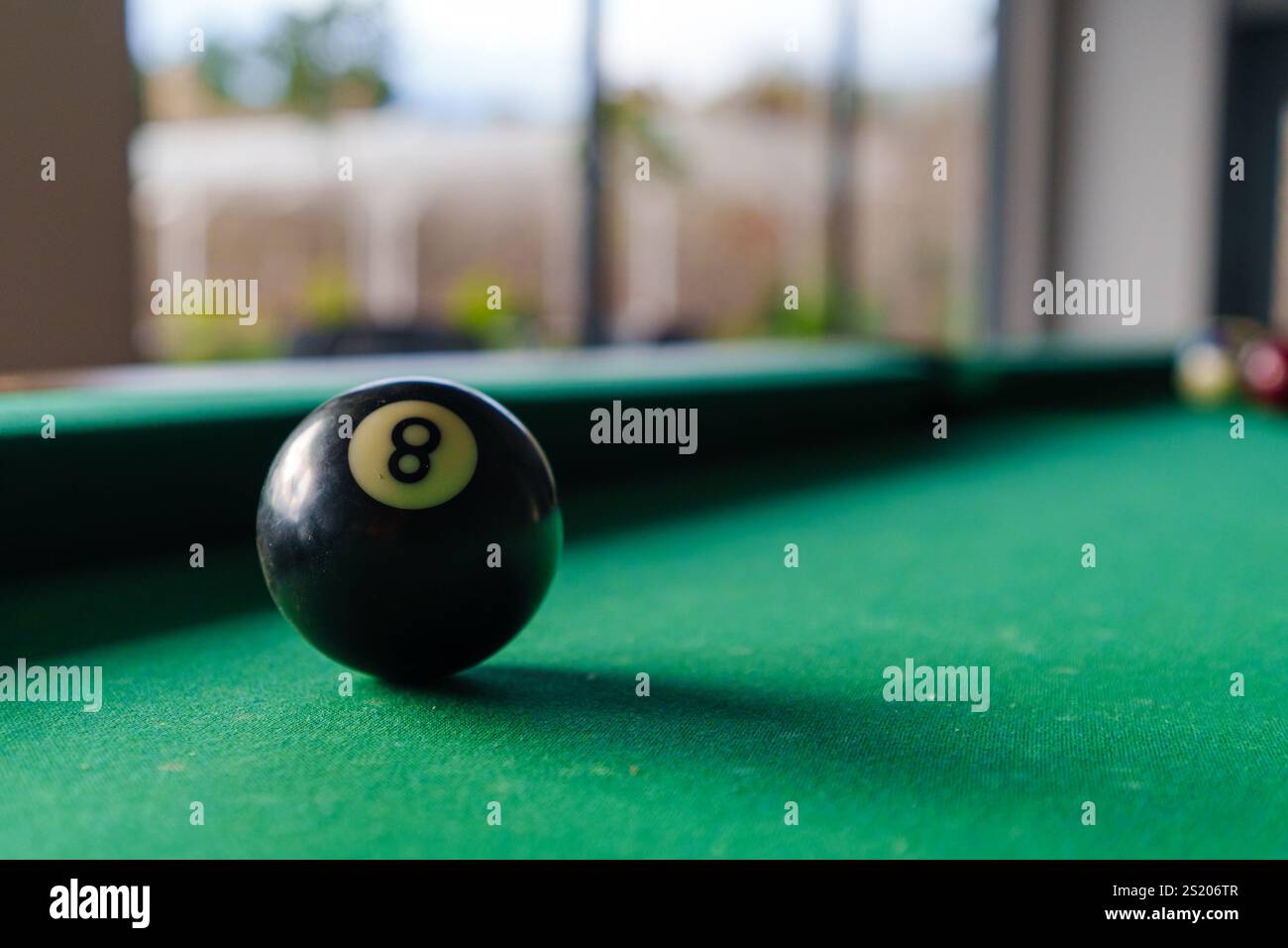 A close-up shot of a pool table highlighting an eight ball in focus ...