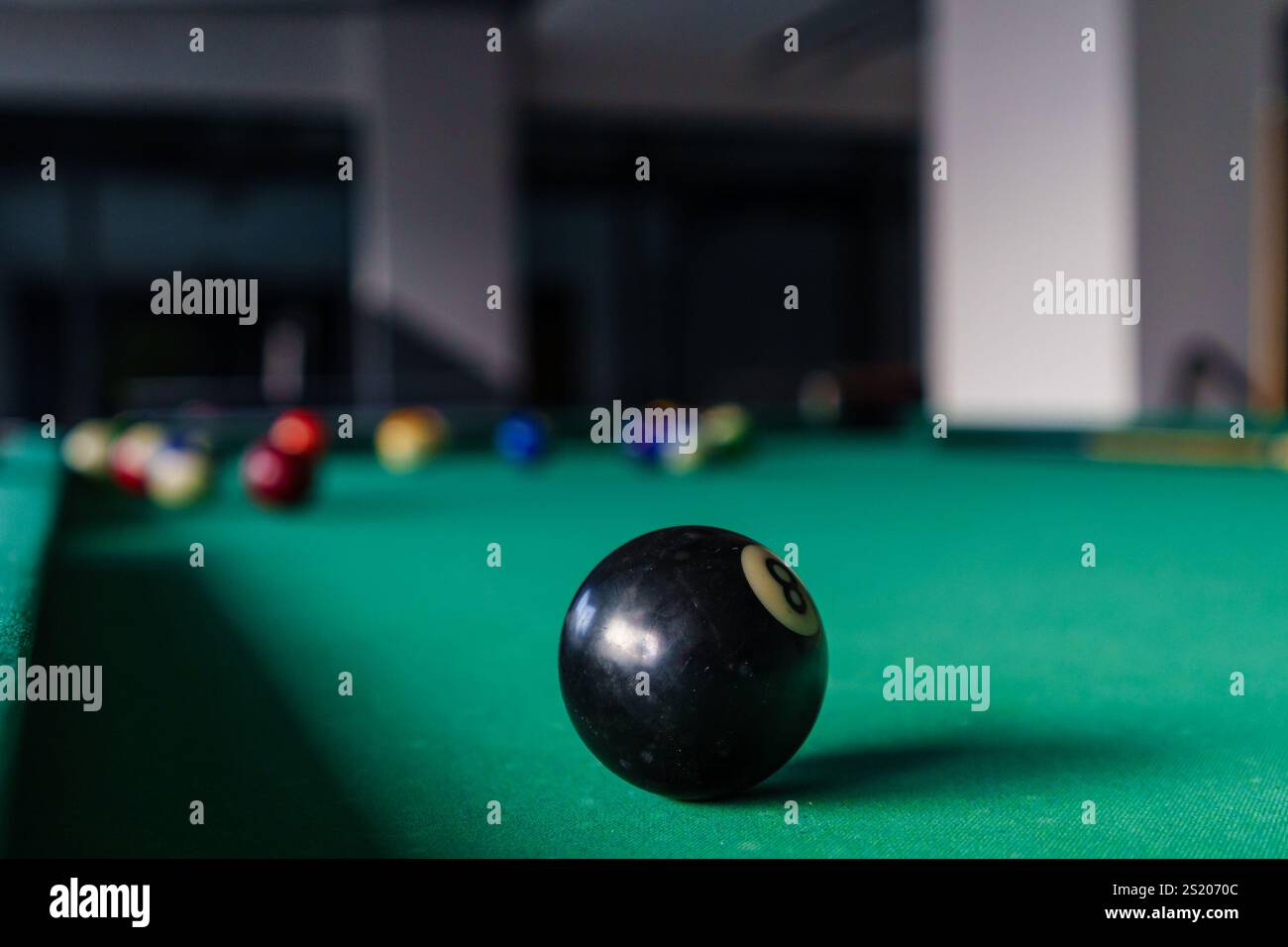 A close-up shot of a pool table highlighting an eight ball in focus ...