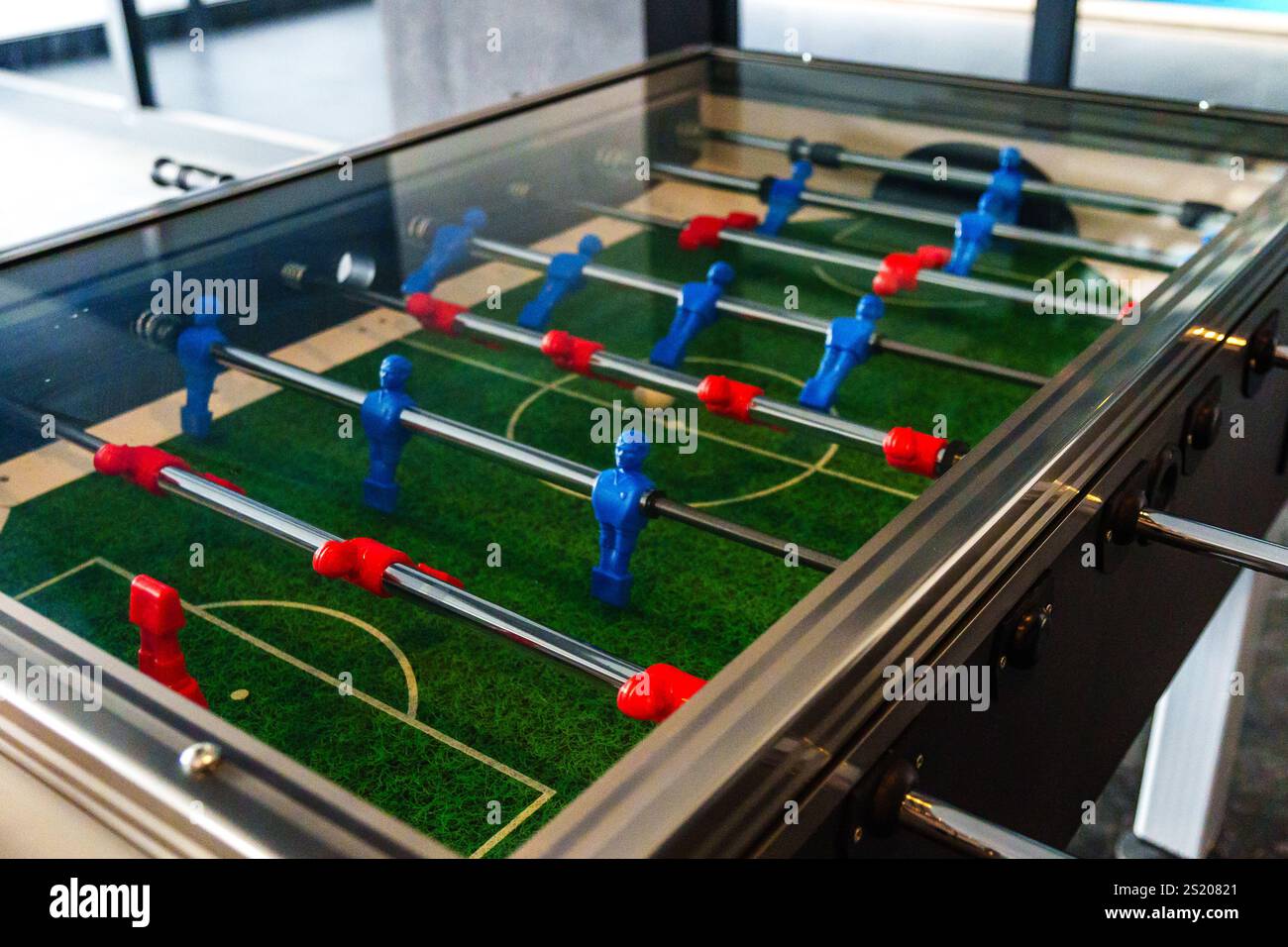 A classic foosball table with red and blue players ready for a ...