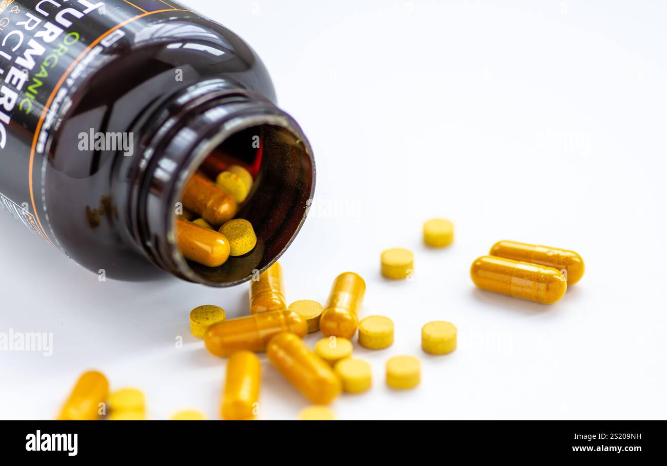 An open bottle of turmeric curcumin health supplement with some of the ...