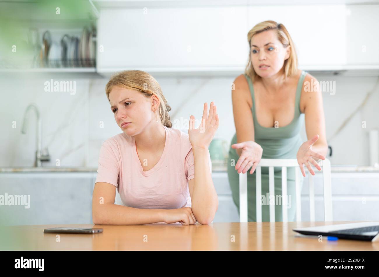 Frustrated teenage girl making dismissive gesture to disgruntled mother ...