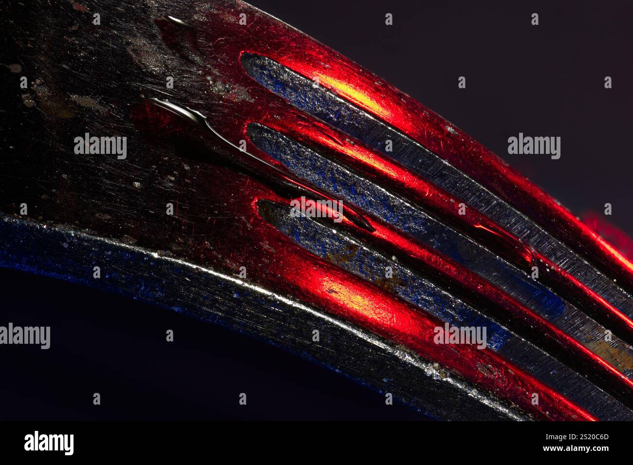 Abstract of tines of a chrome fork with red and blue reflections and a ...