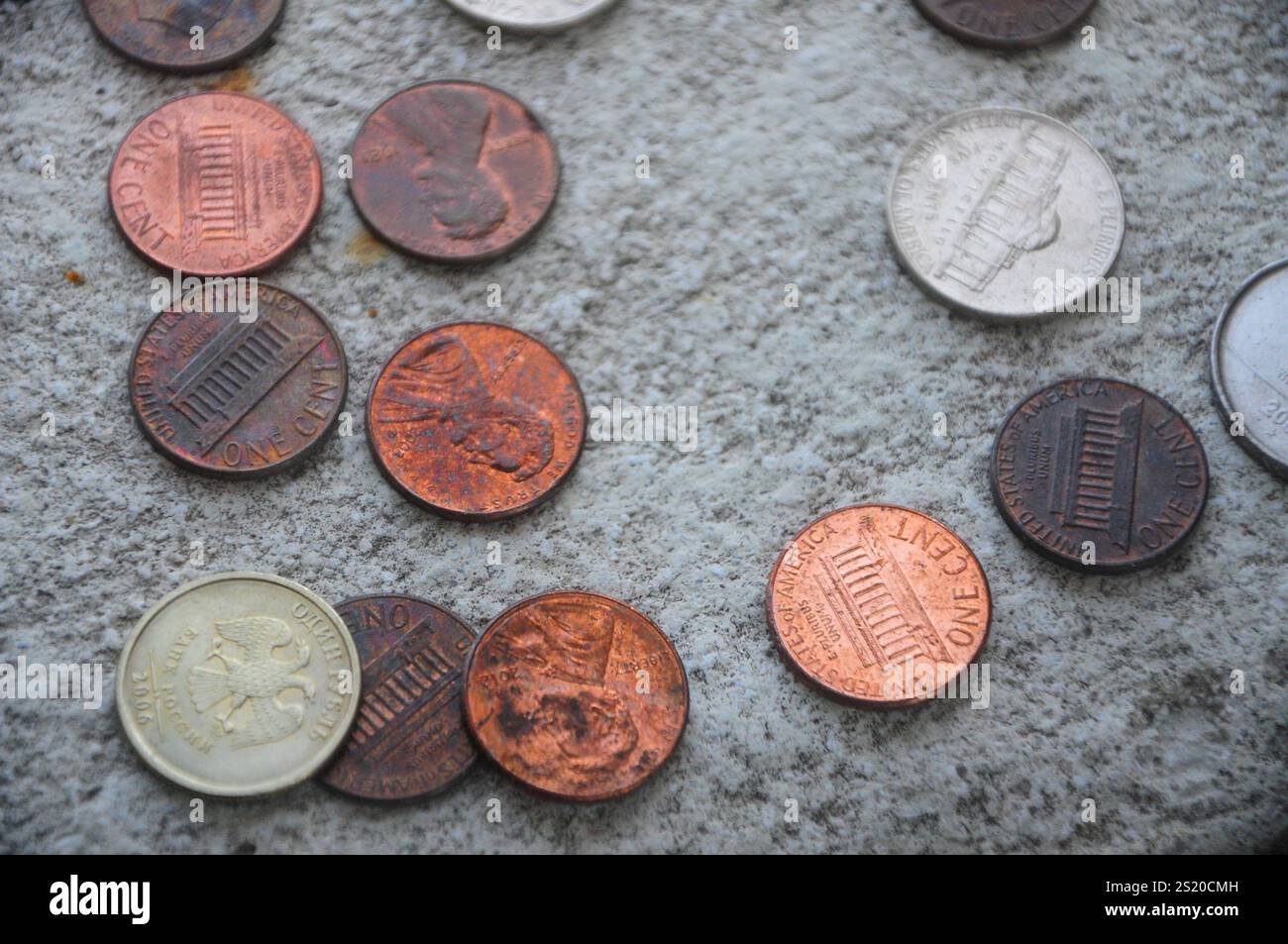 Assorted U.S. coins on textured concrete with copper pennies and ...