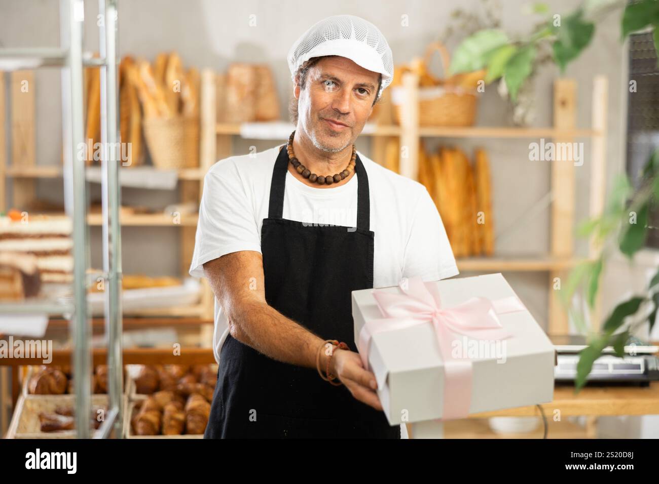 Middle-aged salesman holding cake box in bakery Stock Photo - Alamy
