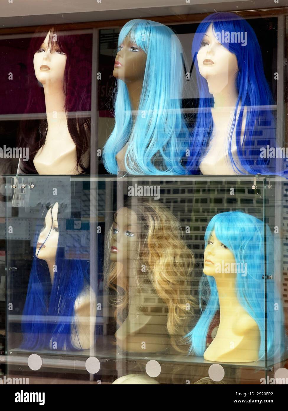 Wigs in shop window assorted colours on model heads Stock Photo - Alamy