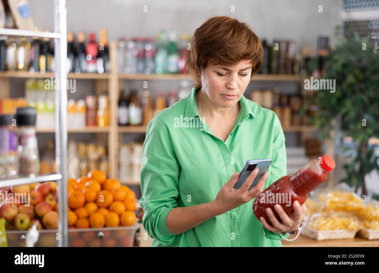 Adult woman scanning qr code of tomato juice Stock Photo - Alamy