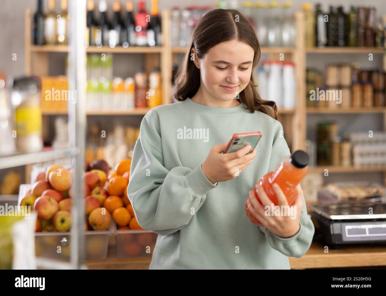 European teen girl customer at shop scans QR code on grapefruit juice ...